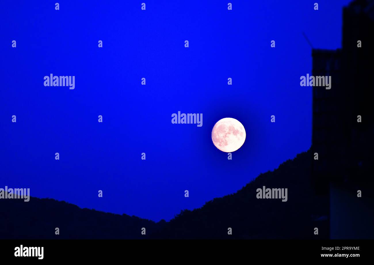 The moon rises behind a mountain Stock Photo - Alamy