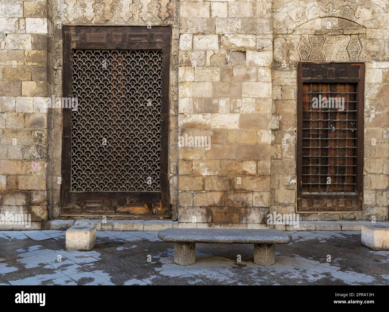 Two wooden windows with decorated iron grid over stone bricks wall and ...