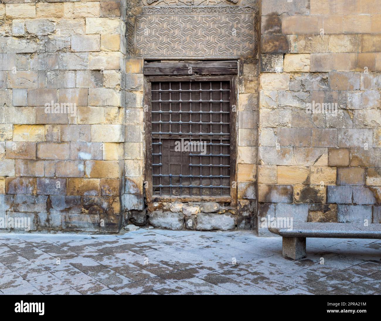 Wooden window with decorated iron grid over stone bricks wall and ...