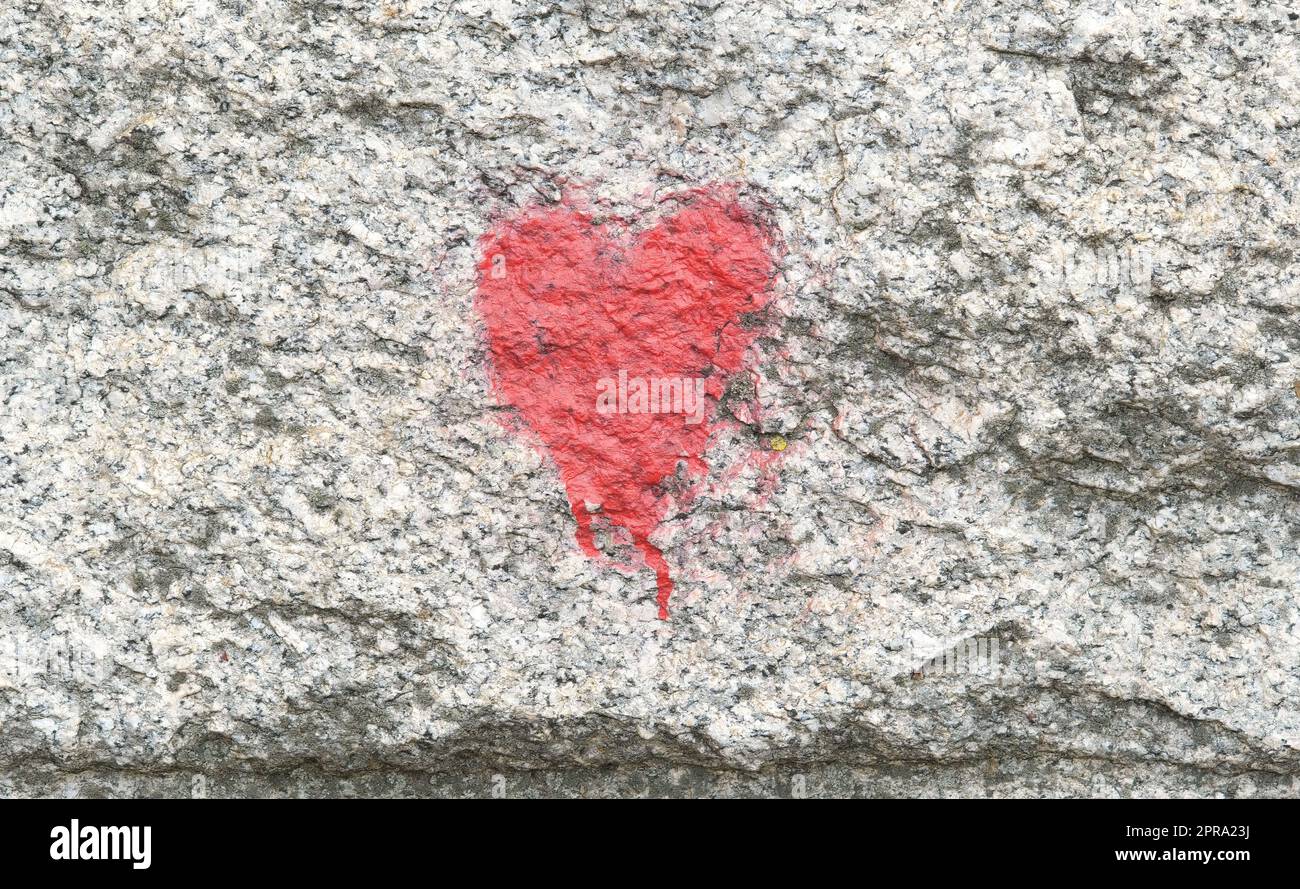 A small generic red heart symbol painted on a wall, heart icon front ...