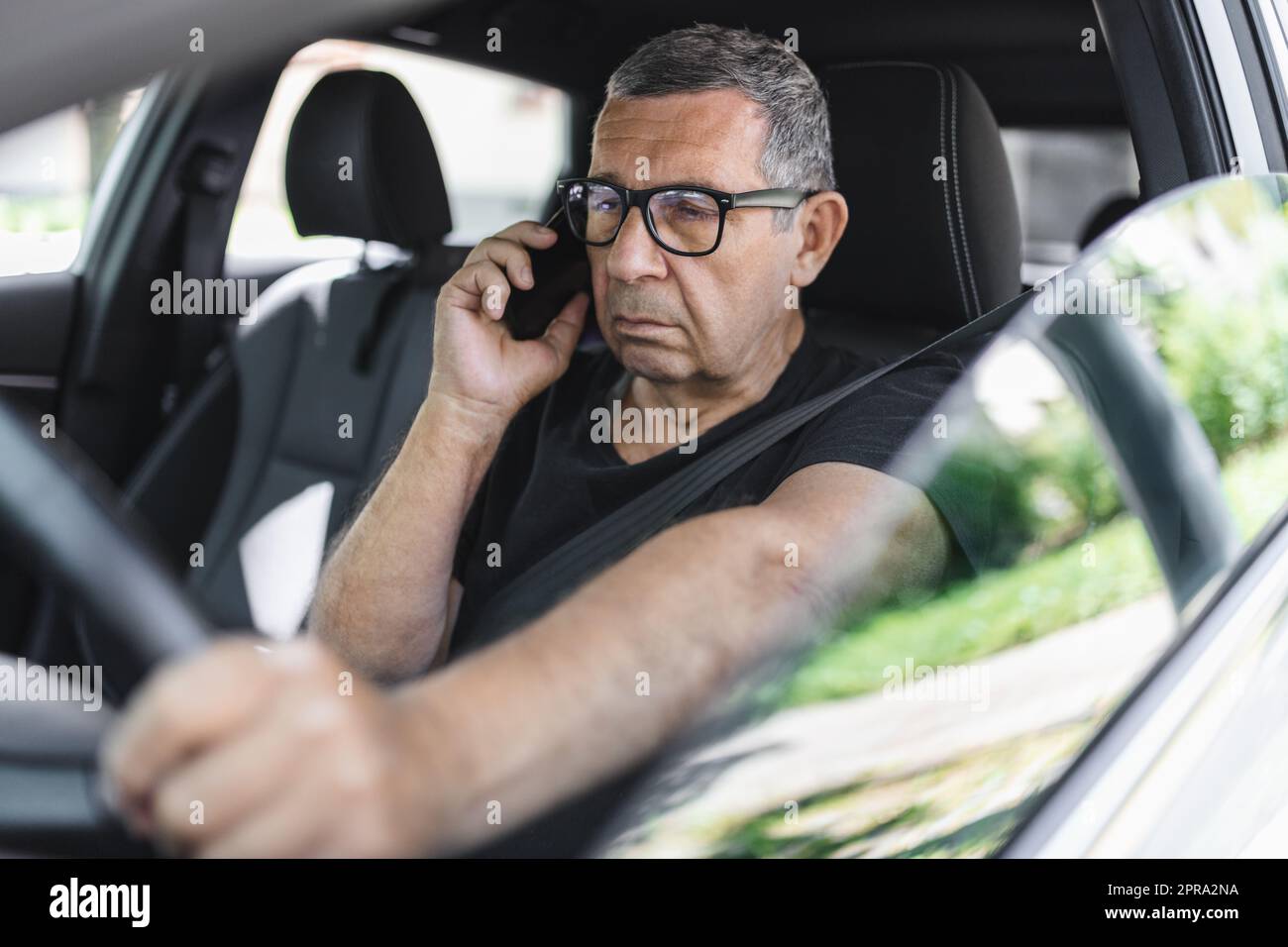 Senior in his 70s driving a car and using his mobile phone Stock Photo ...