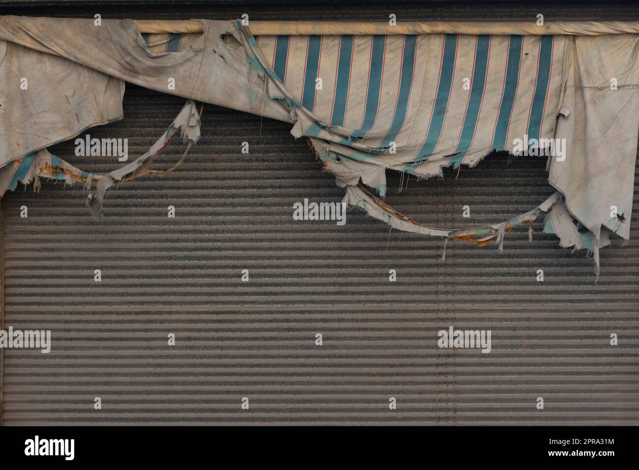 Torn and ruined shop sun shader at stor front Stock Photo - Alamy
