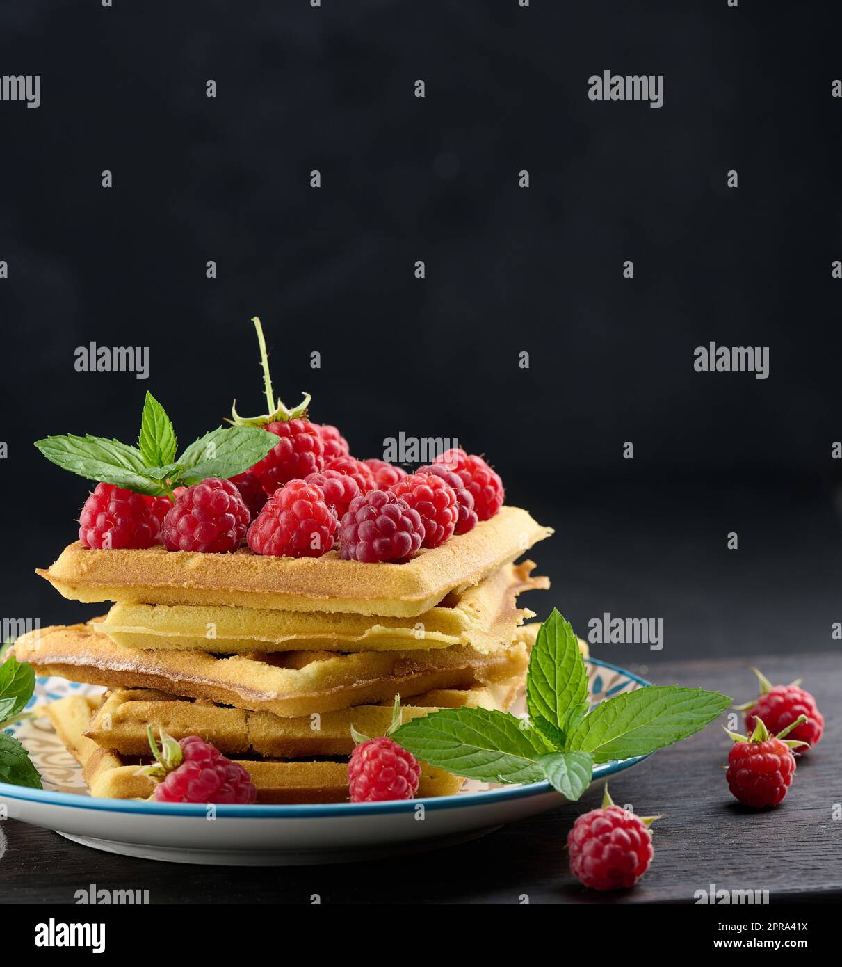 Stack of baked Belgian waffles with ripe red raspberry, green mint ...