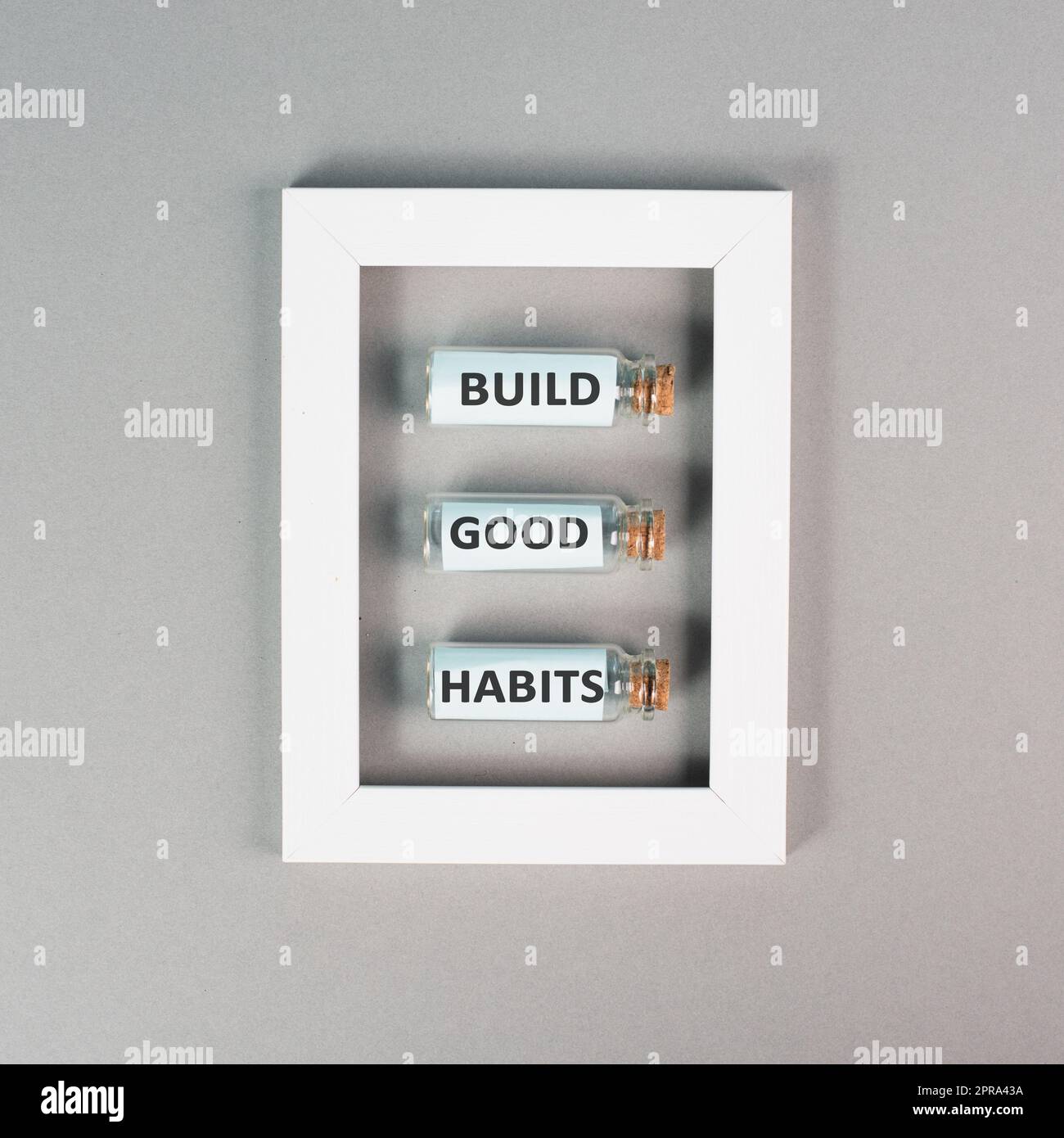 The words build good habits are standing on glass bottles in a frame ...