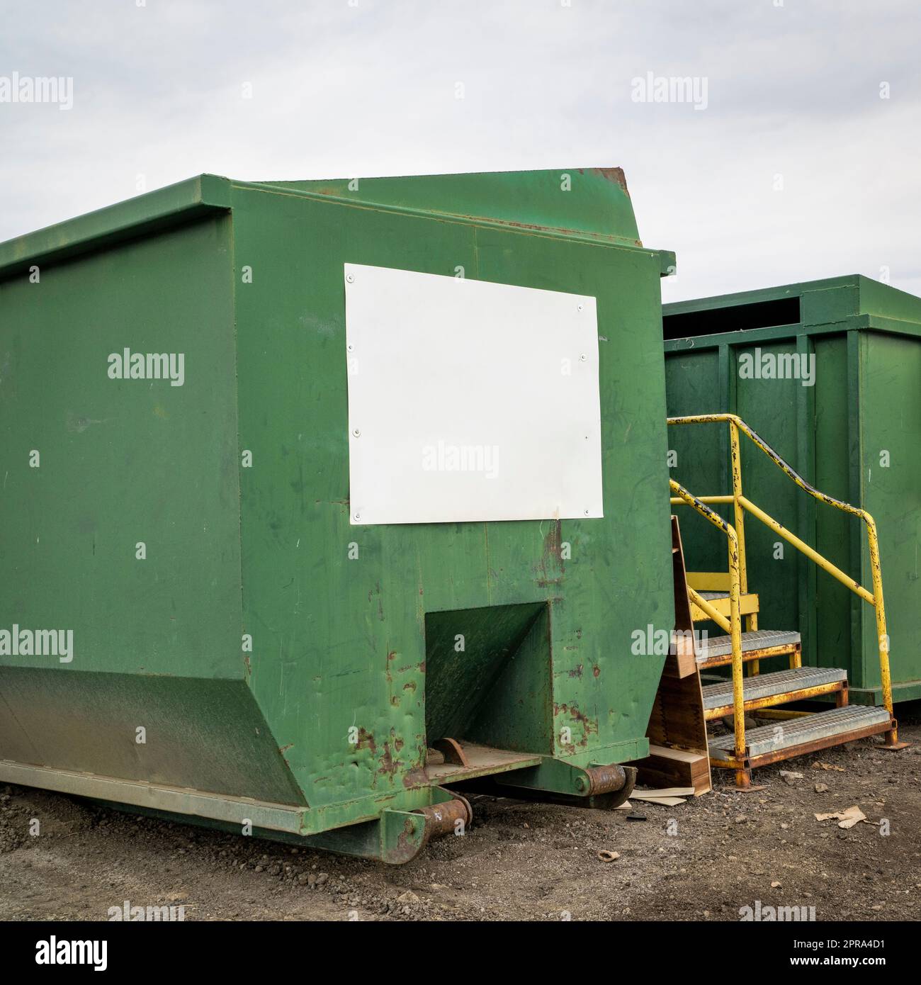 green steel industrial container with a white blank sign at recycling ...