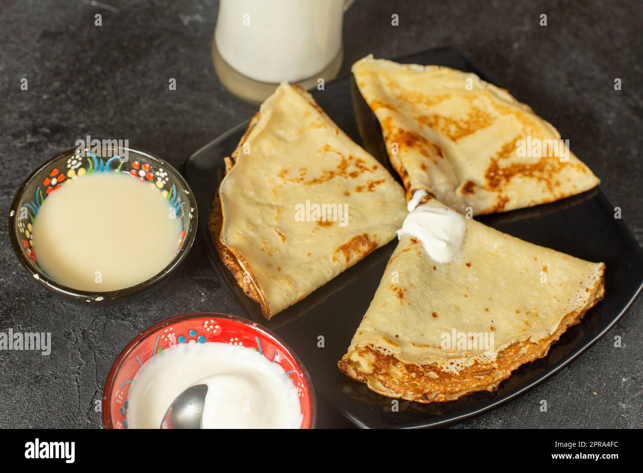 front view delicious pancakes with milk inside black plate on the dark ...