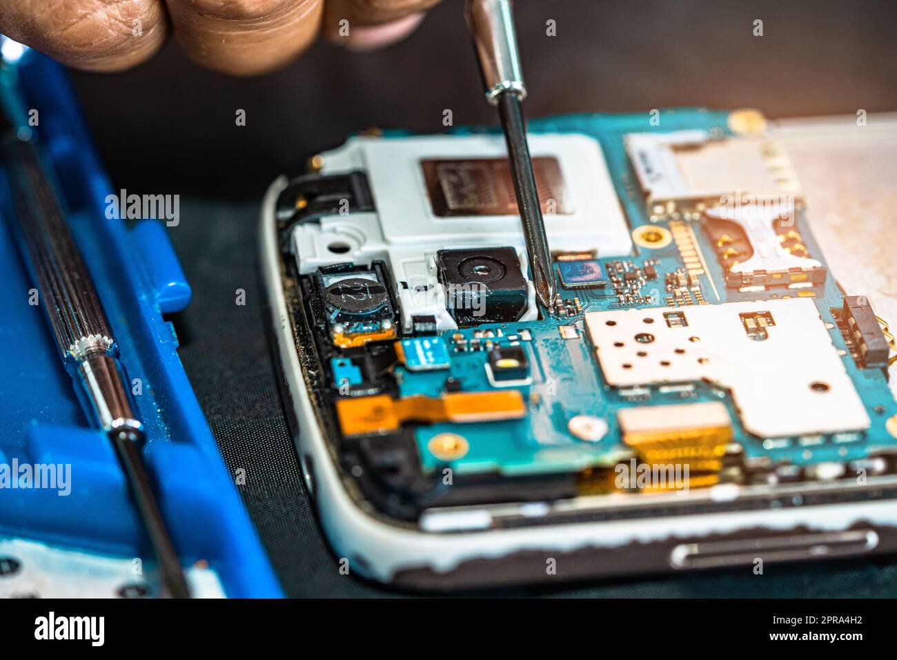 Technician repairing inside of mobile phone by soldering iron ...