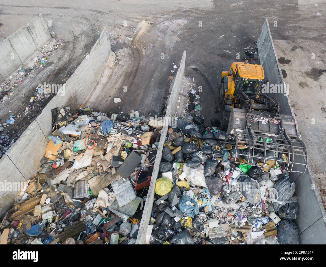 Wheeled loader operating on landfill site, carrying and dumping waste ...