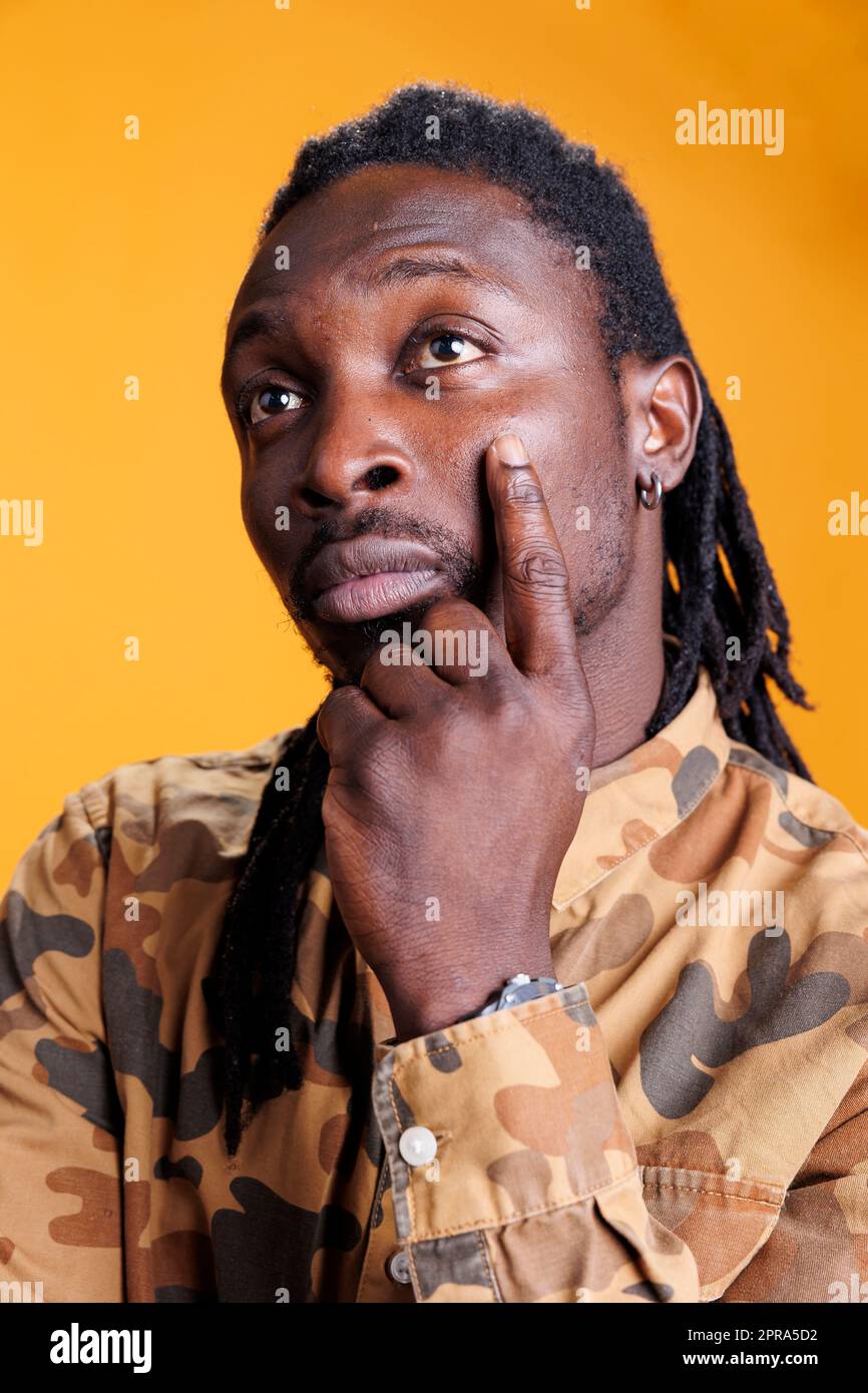 Thoughtful man thinking at business ideas in studio over yellow ...