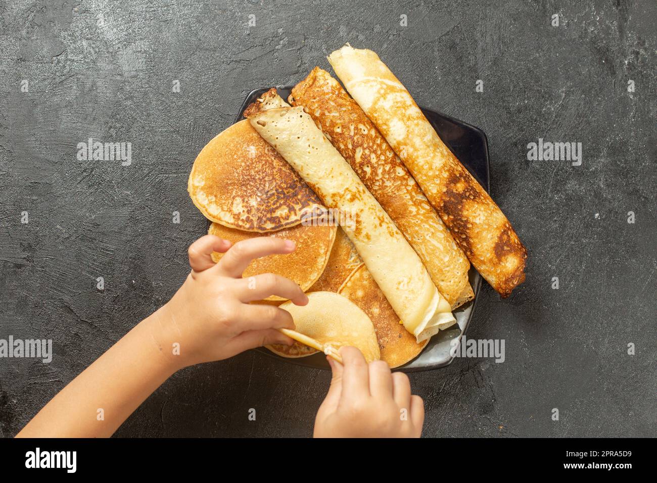 top view delicious pancakes rolled inside black plate on the dark ...