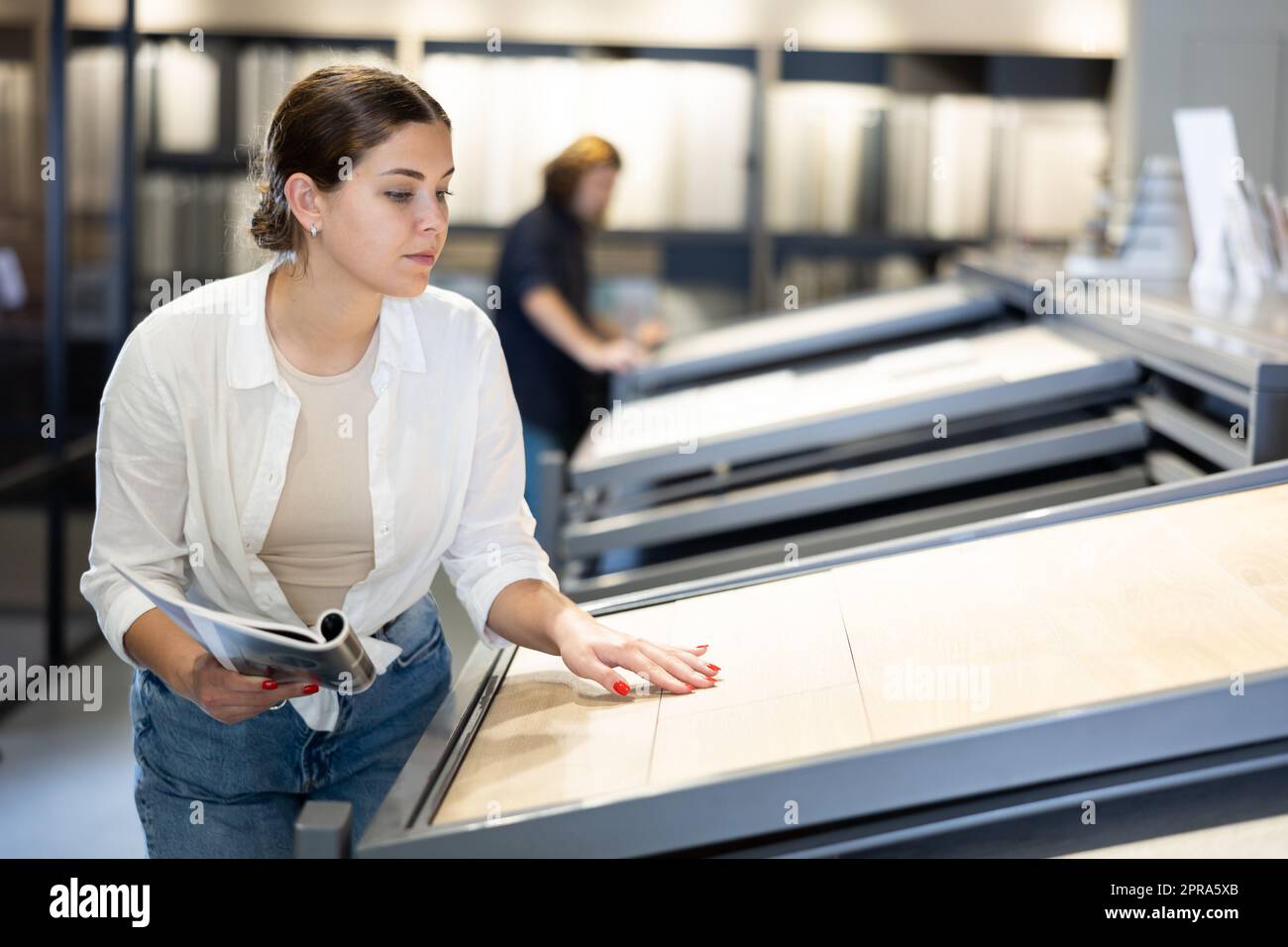 in store,female buyer carefully examines laminate sample. Woman chooses ...