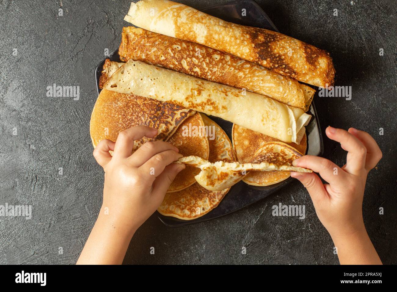 top view rolled pancakes inside black plate getting eat by female on ...
