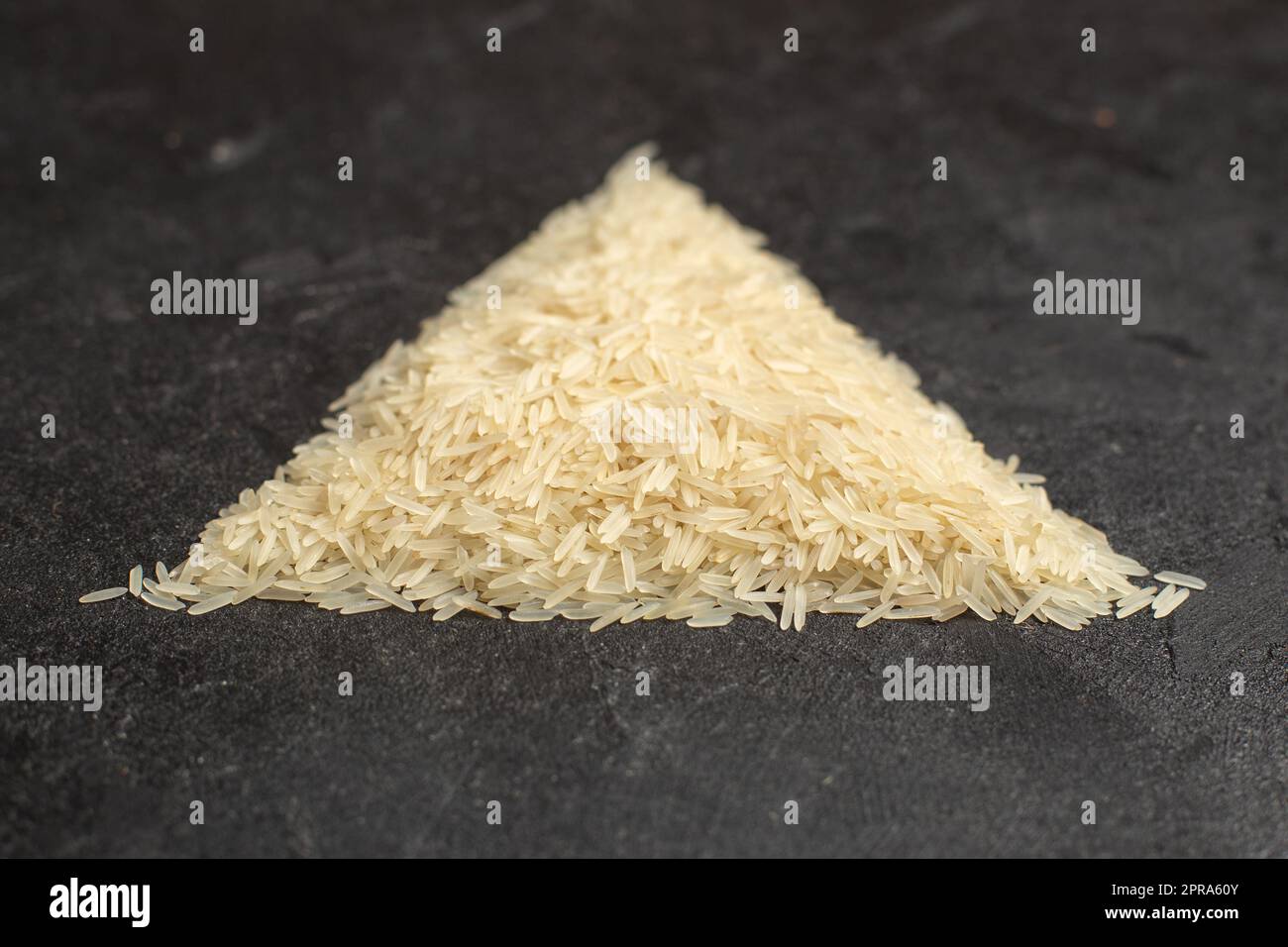 front view raw rice granules forming triangle shape on the dark ...