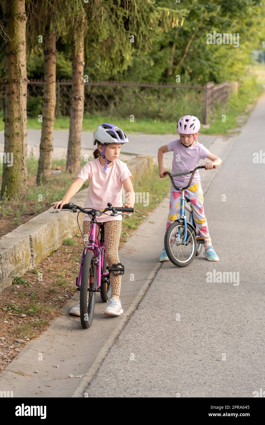 Two elementary school age girls, children biking, cycling, riding their ...