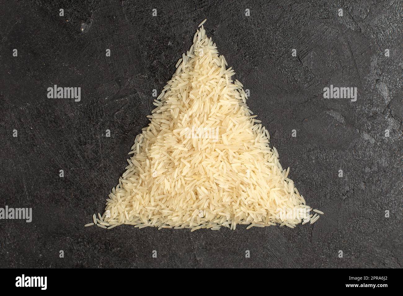 top view triangle shape made by raw rice on the dark background rice ...