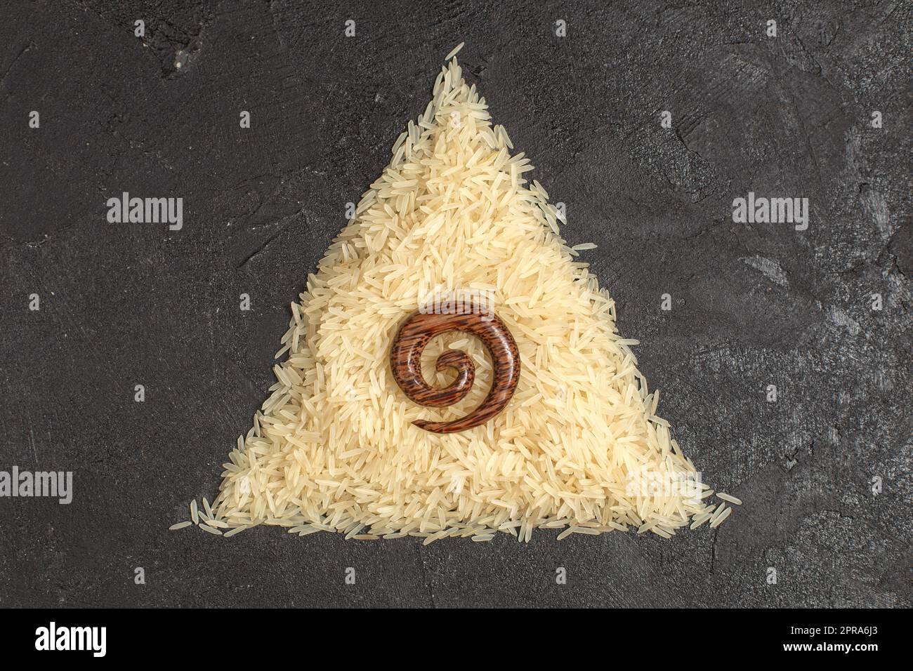 top view raw rice forming triangle shape on the dark background food ...