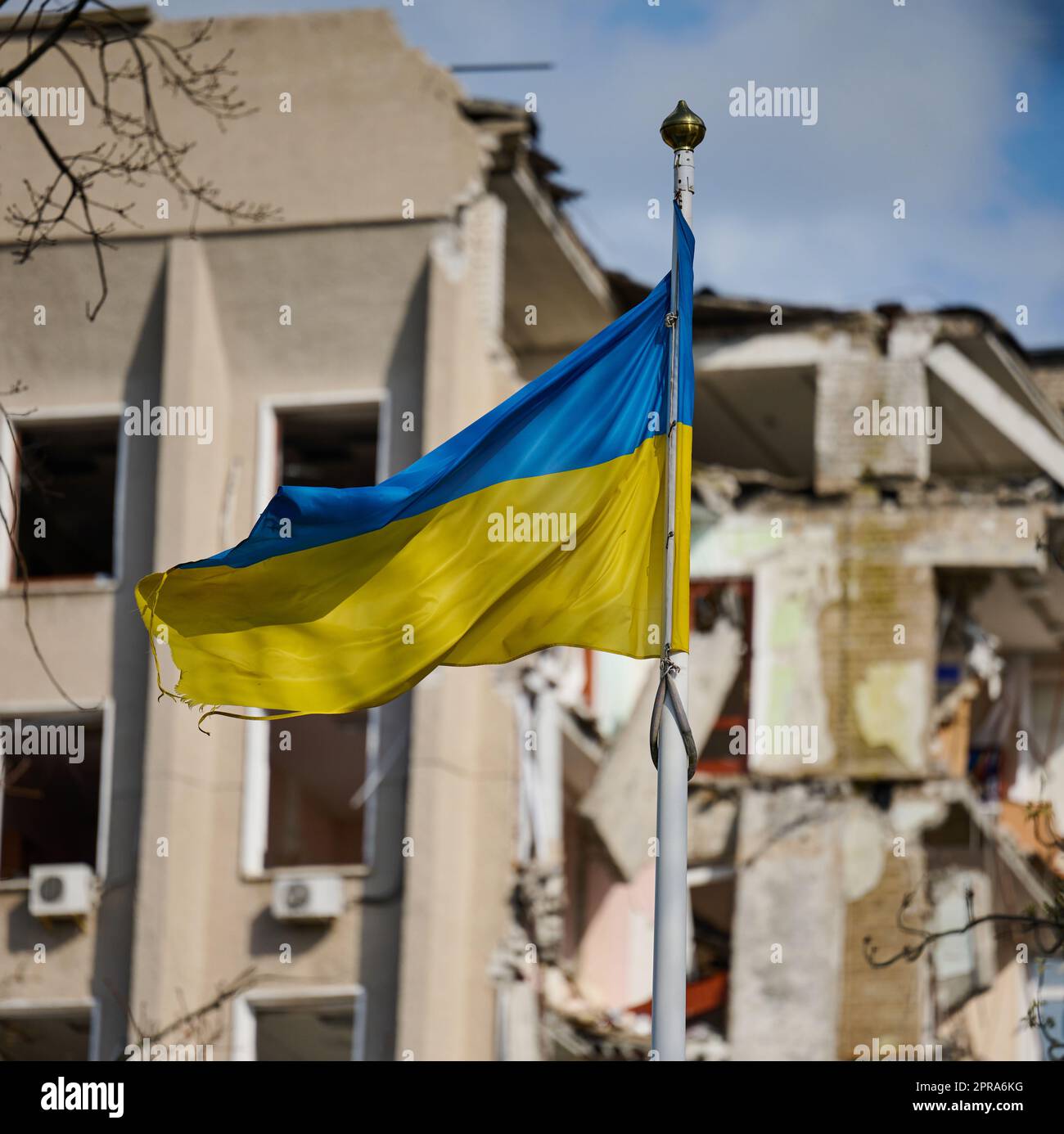 Flag of Ukraine against the background of a destroyed building in ...