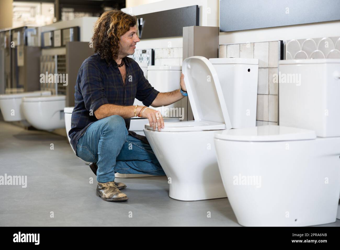in plumbing department, male buyer checks for defects of toilet before ...