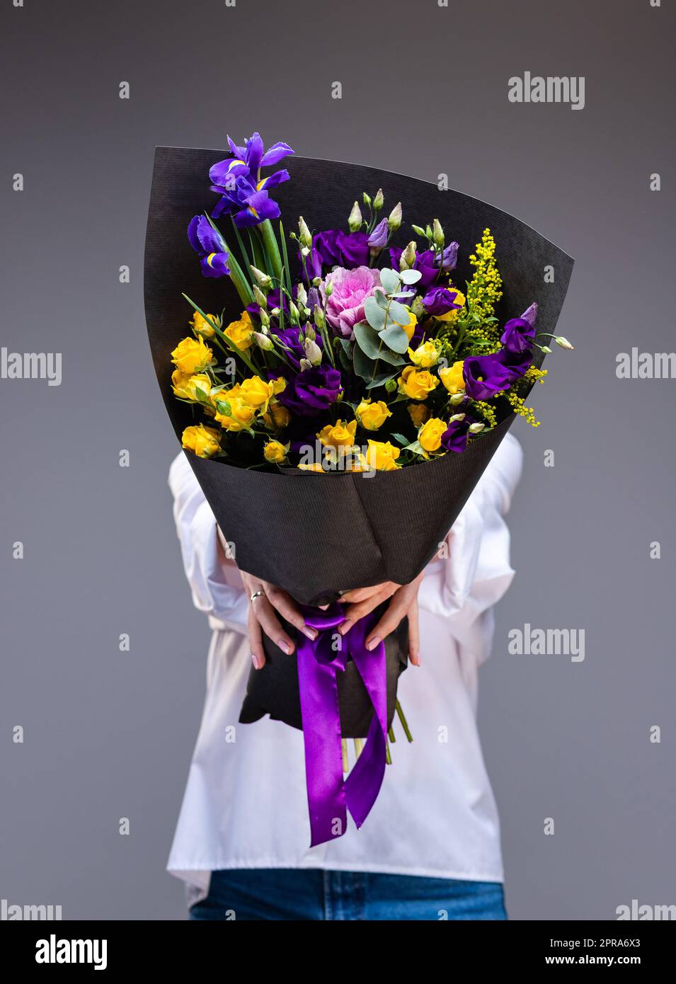Woman holds out a bouquet wrapped in black paper, covering her face ...