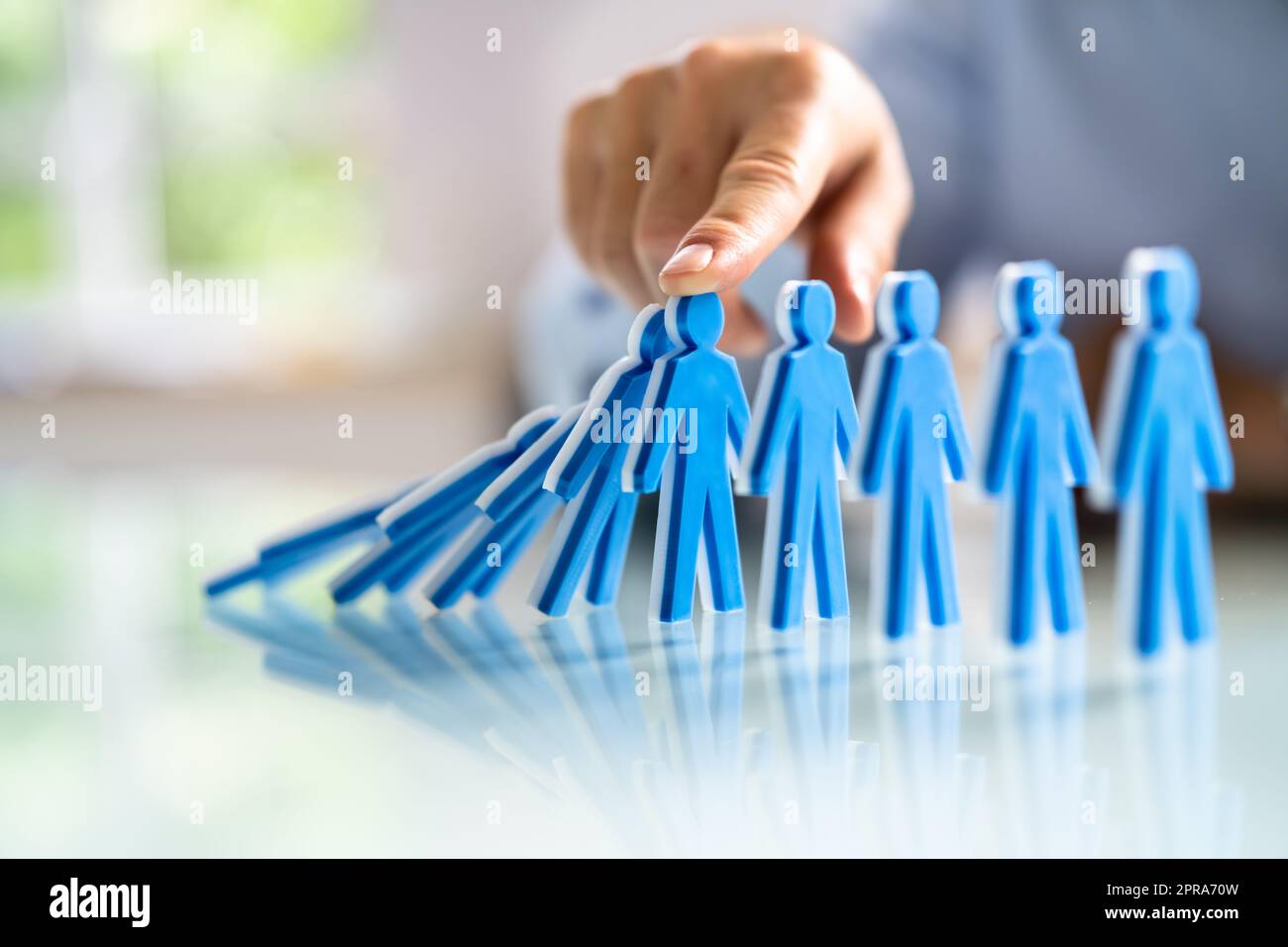 Businessperson Stopping Falling Persons On Desk Stock Photo - Alamy