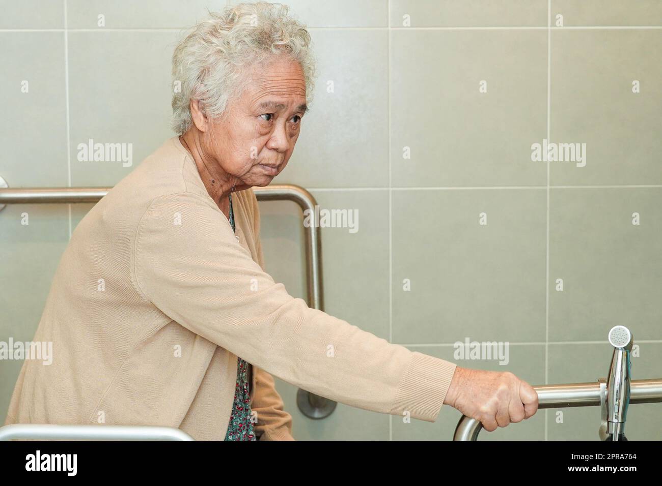 Asian elderly old woman patient use toilet support rail in bathroom ...
