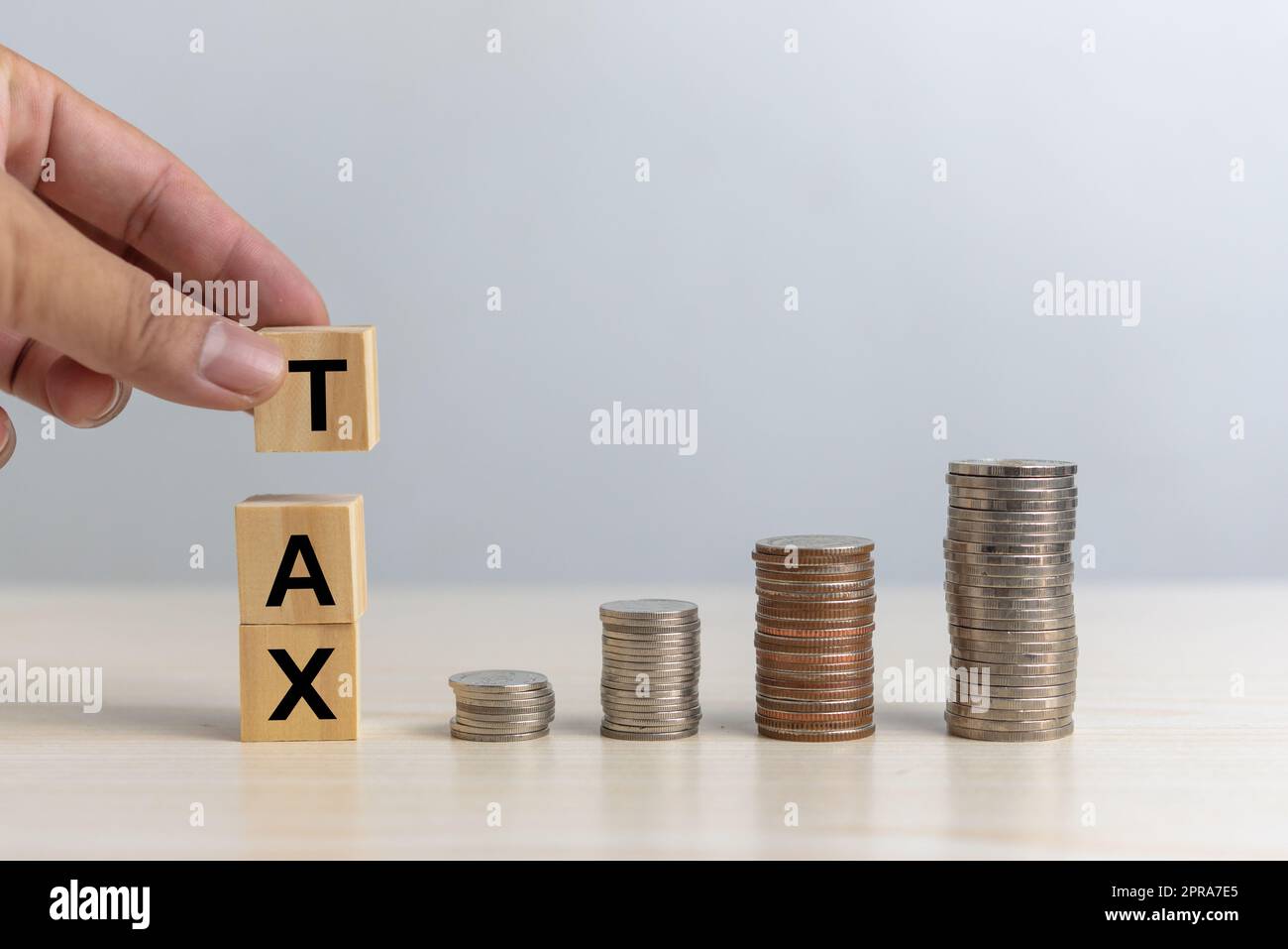 Hand holding wood cube block TAX and coin money on desk. Business ...