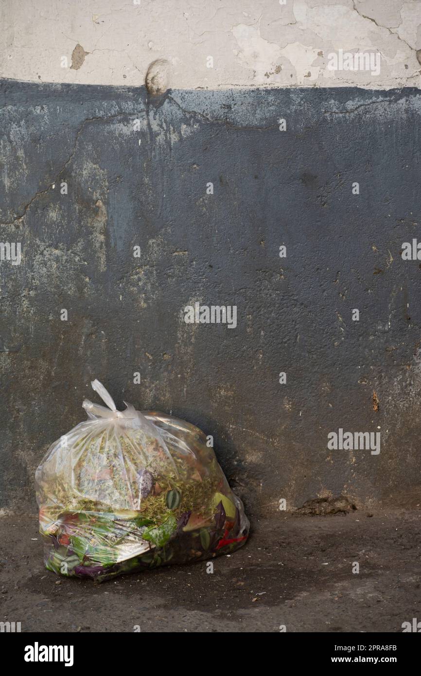 Plastic bag full of trash in front of dirty wall Stock Photo - Alamy
