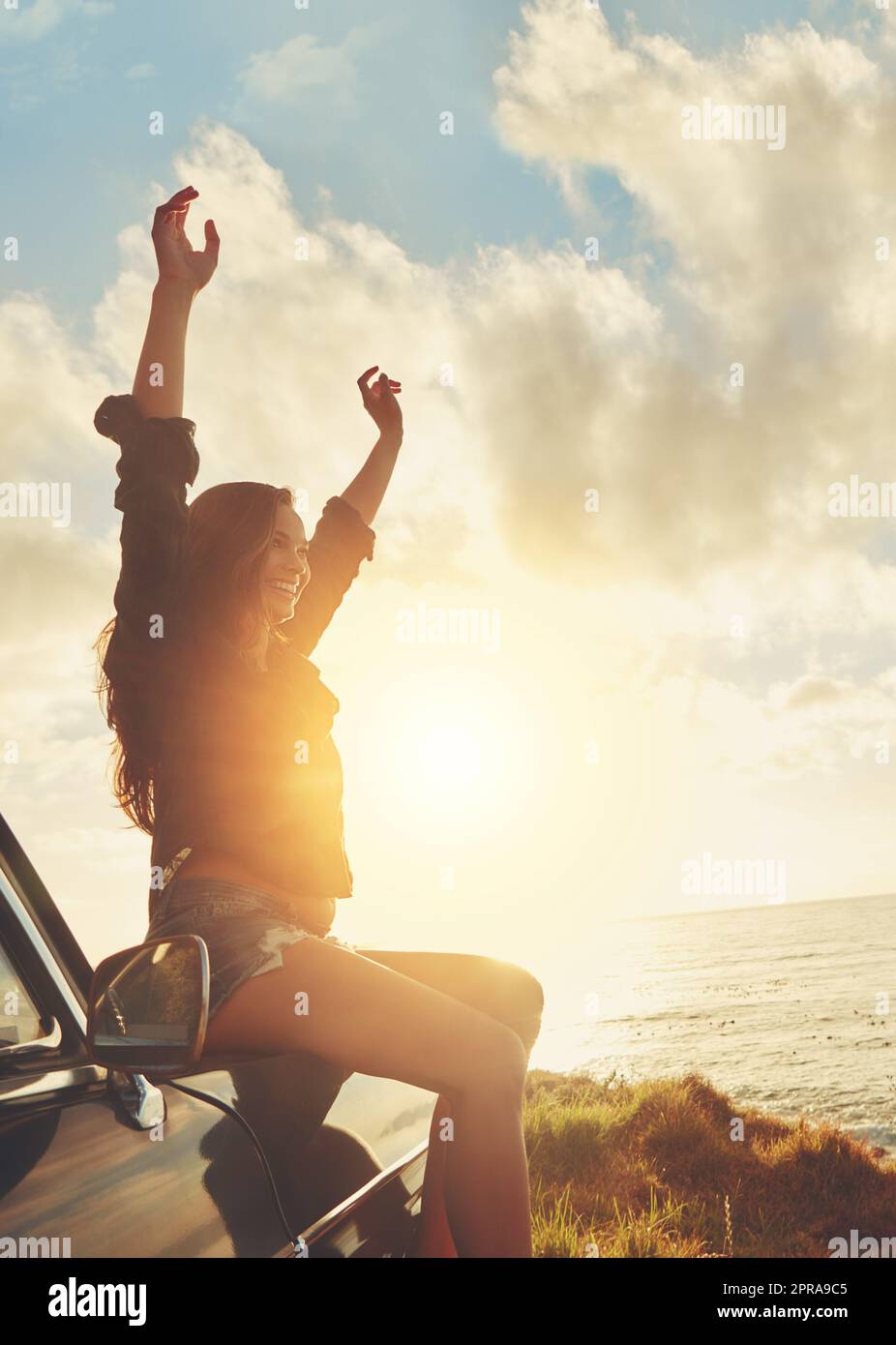 Shes arrived. a young woman sitting on the hood of her car while on a ...