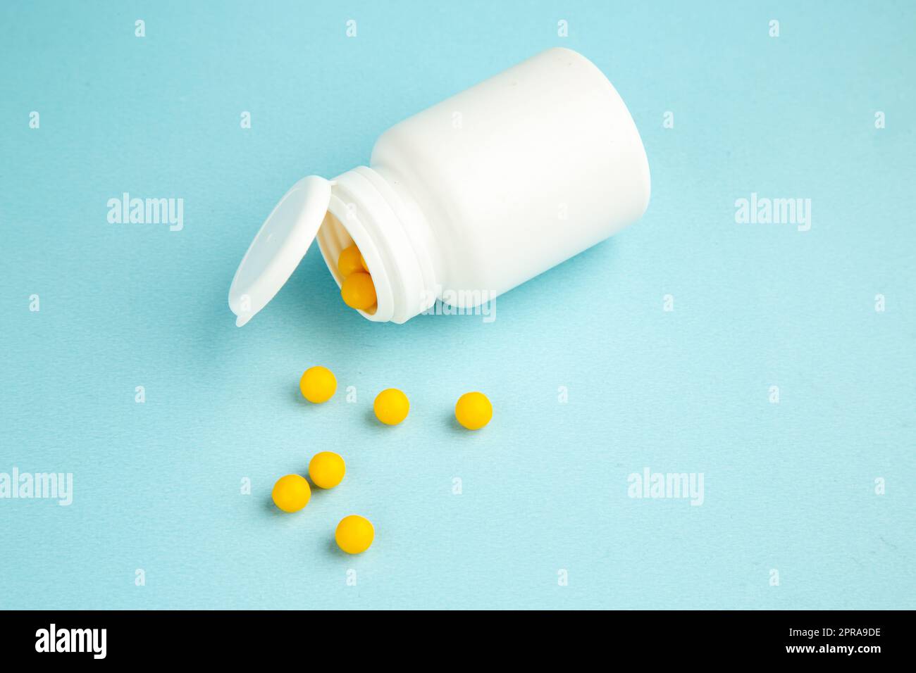 above view little pill can with yellow vitamine pills on blue ...