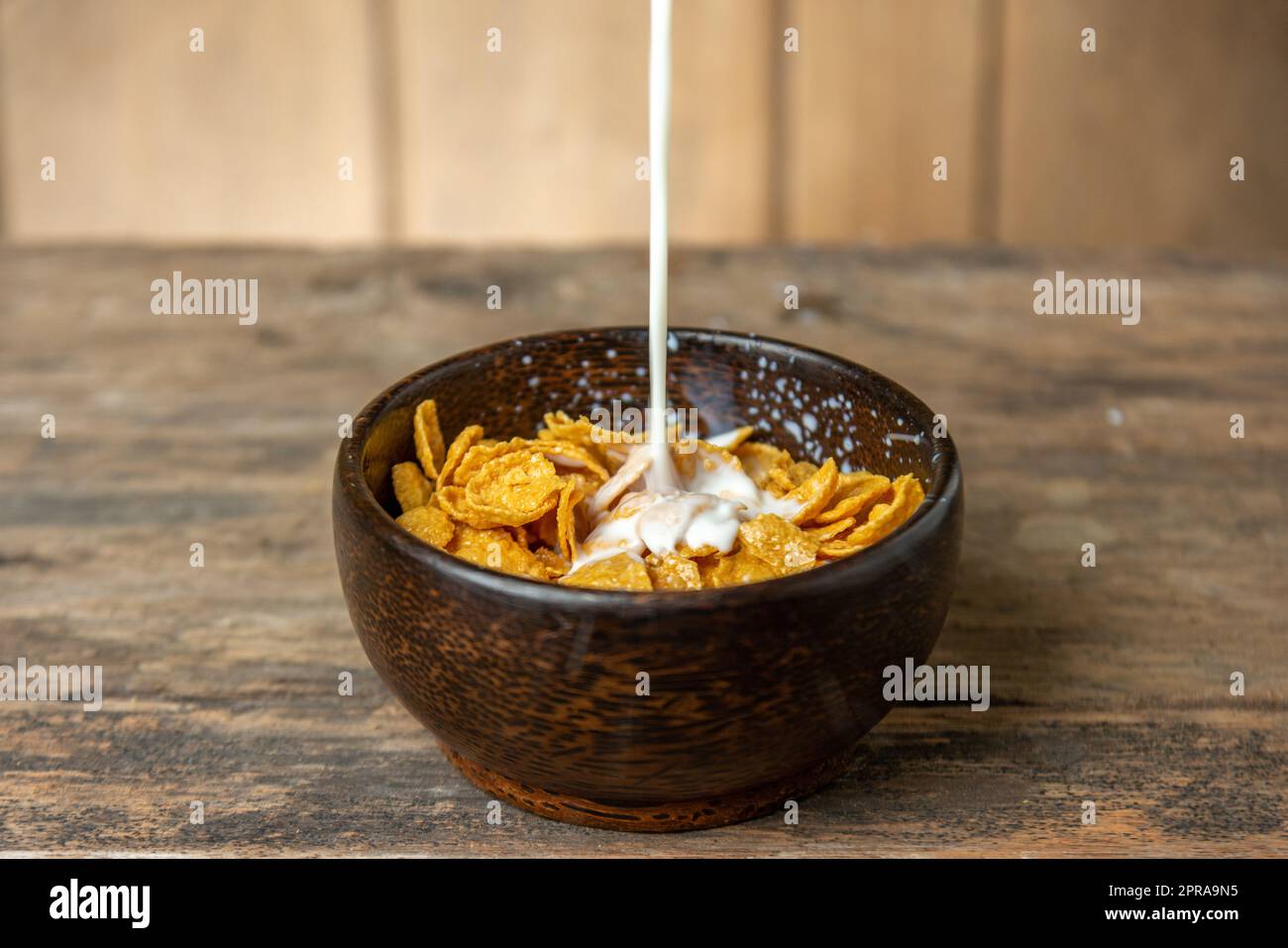 Cereal in wooden bowl with milk splash on blurred wooden Stock Photo ...