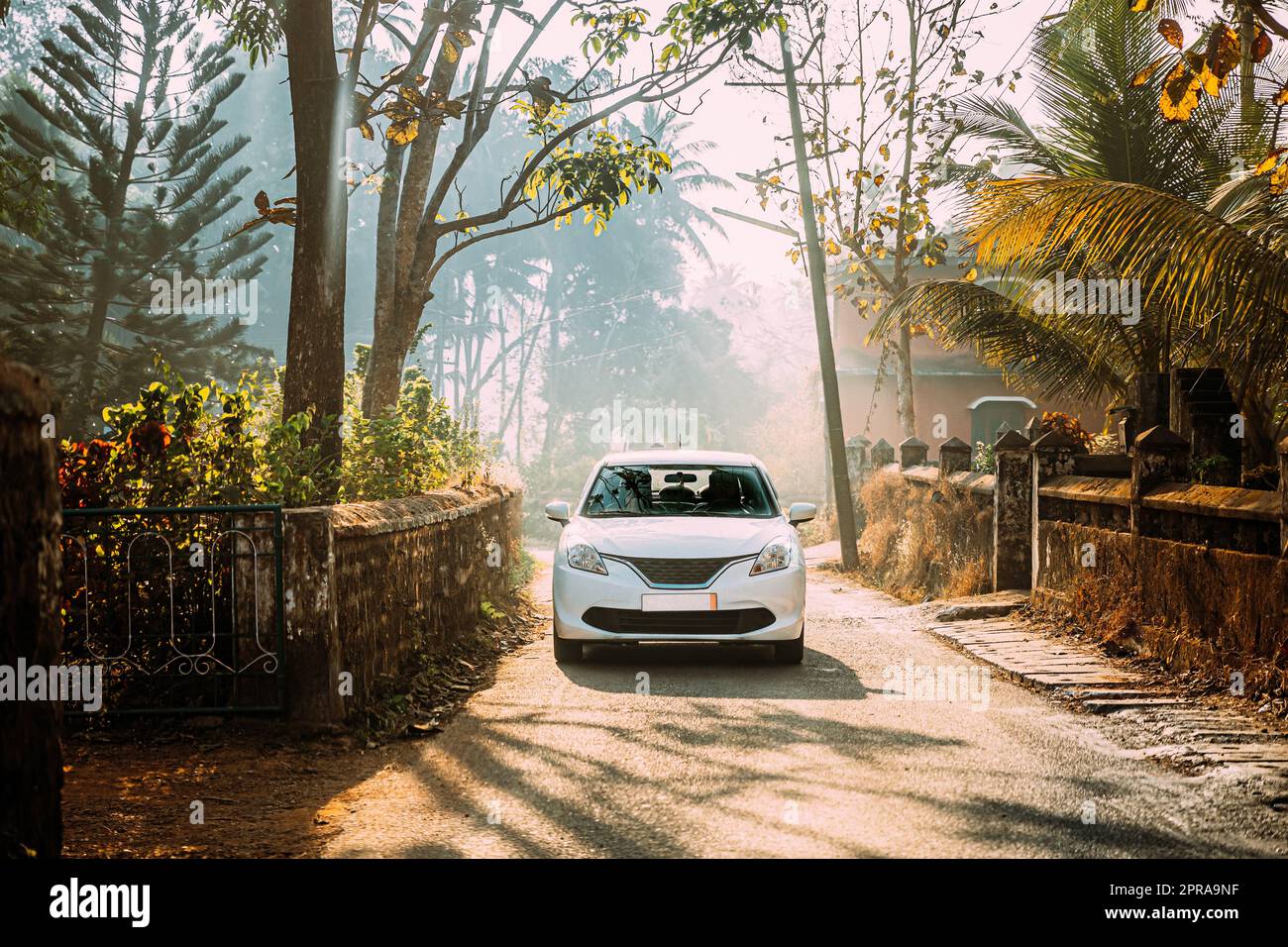 Goa, India. White Small Car Moving On Country Road Through An Indian ...