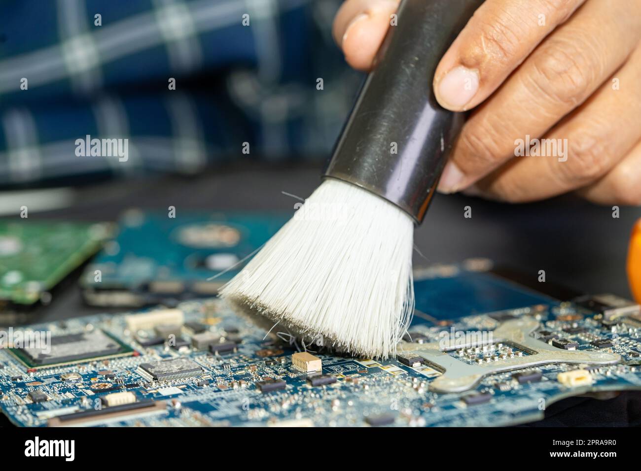 Technician use brush and air blower ball to clean dust in circuit board ...
