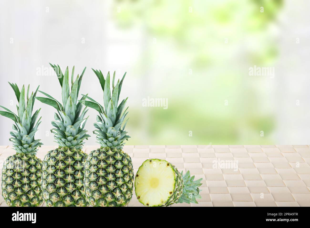 Fresh ripe pineapple fruits on a table over a abstract blurred bright ...