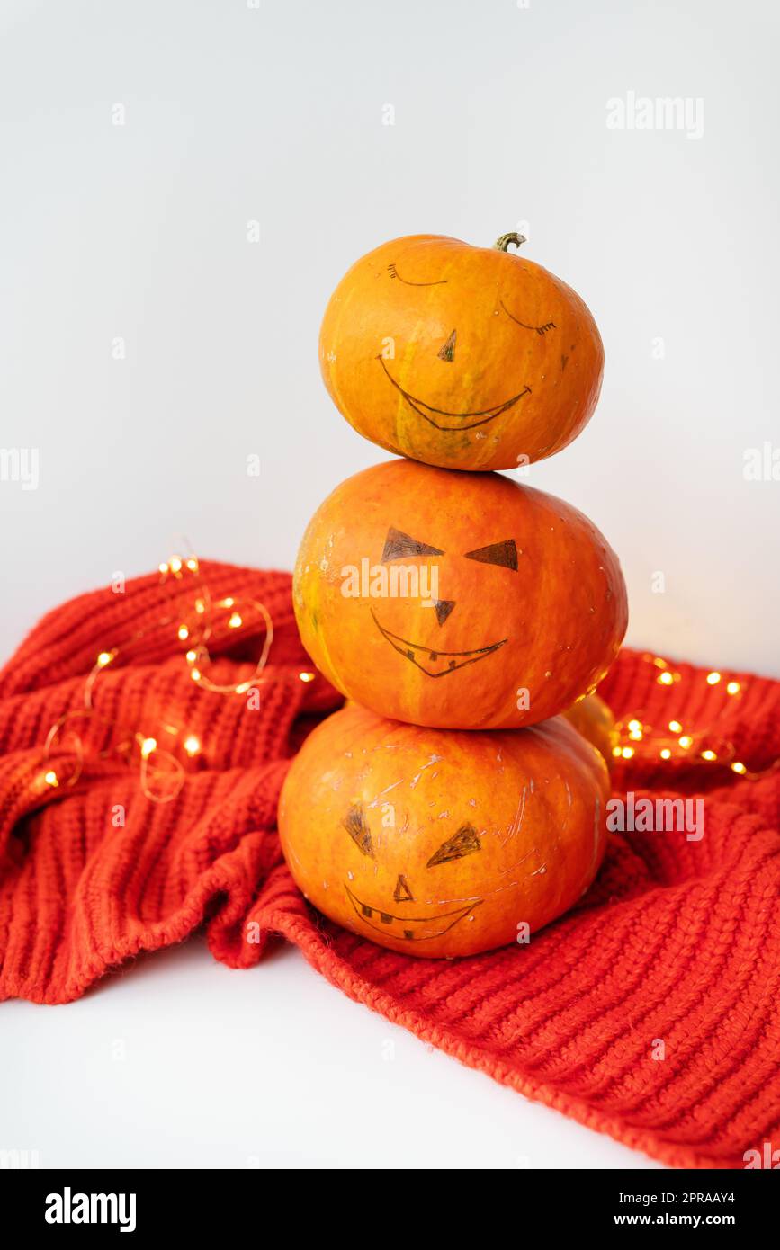 Three pumpkins with a painted face on a red sweater. The concept of the ...