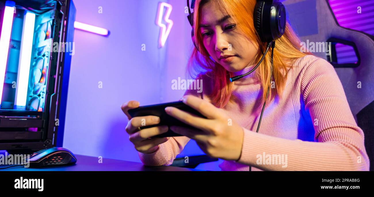 Gamer in playing video game online with smartphone with neon lights she ...