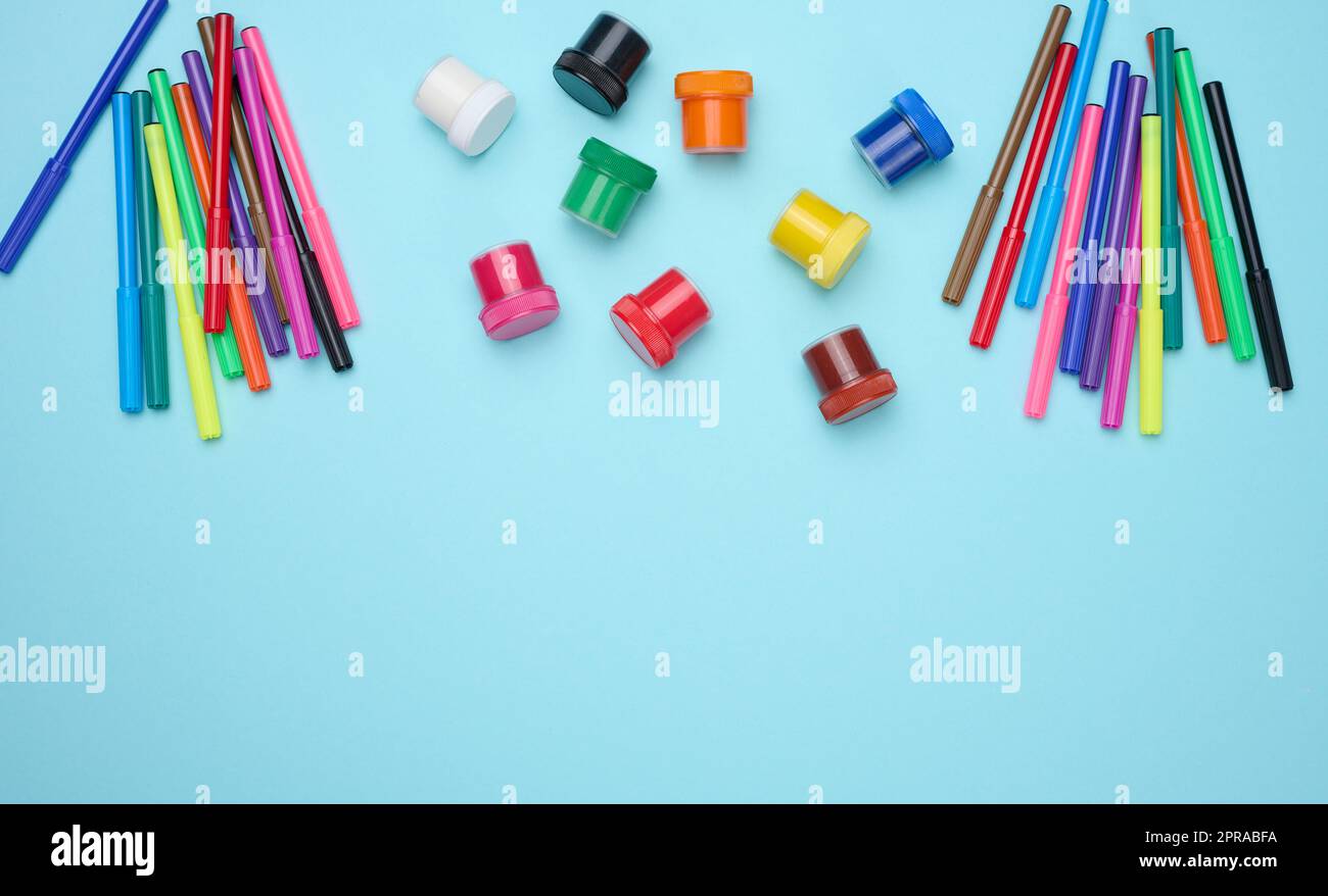 Multi-colored felt-tip pens and acrylic paint in a plastic jar on a ...
