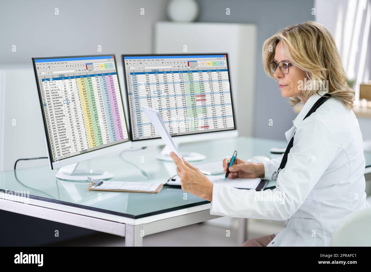 Hospital Doctor Using Spreadsheet For Billing Codes On Desktop Stock ...