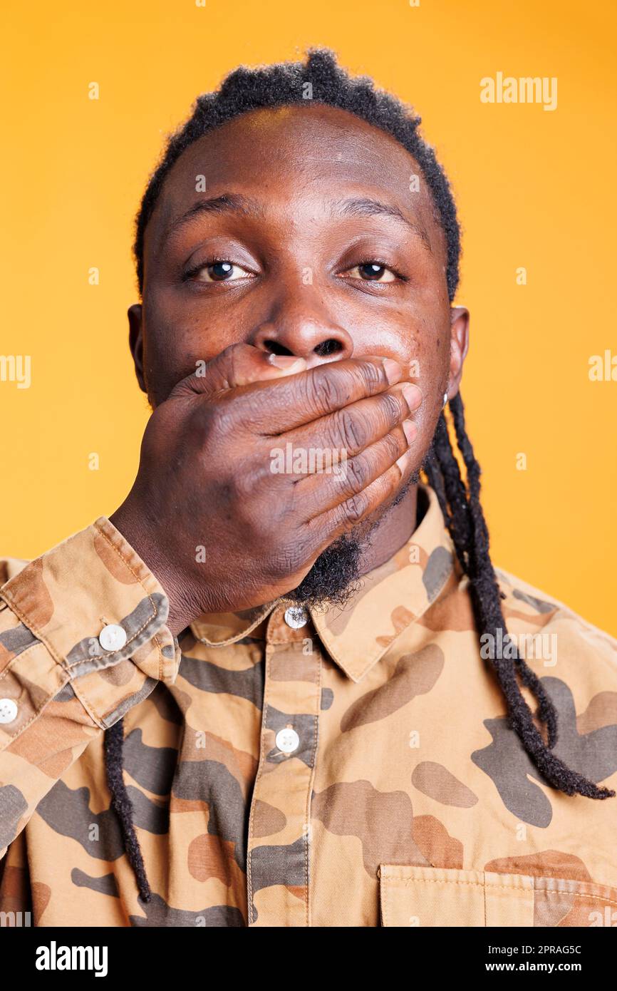African american man covering mouth with palms, doing doing three wise ...