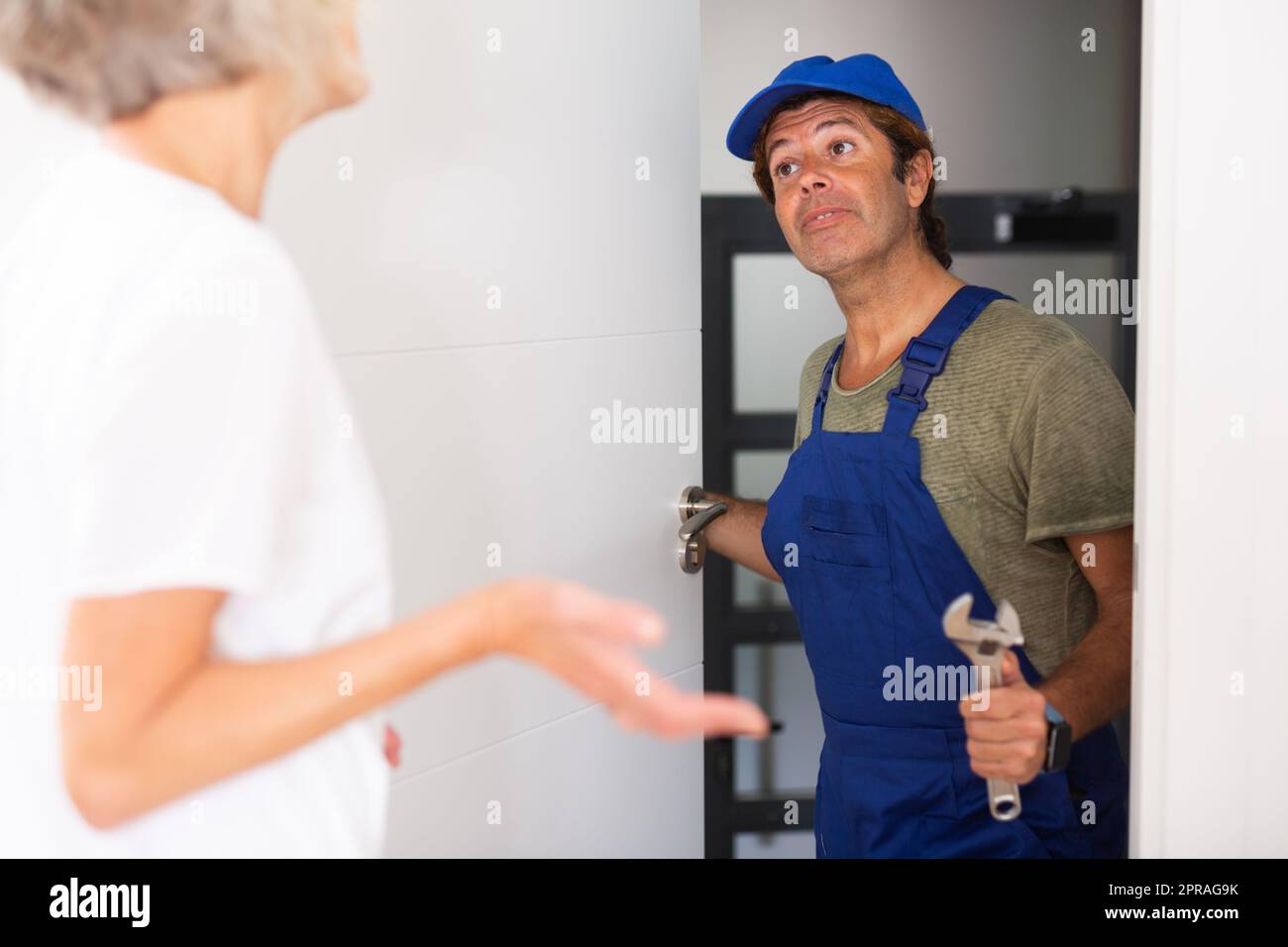 Skilled male plumber talking with woman homeowner Stock Photo - Alamy
