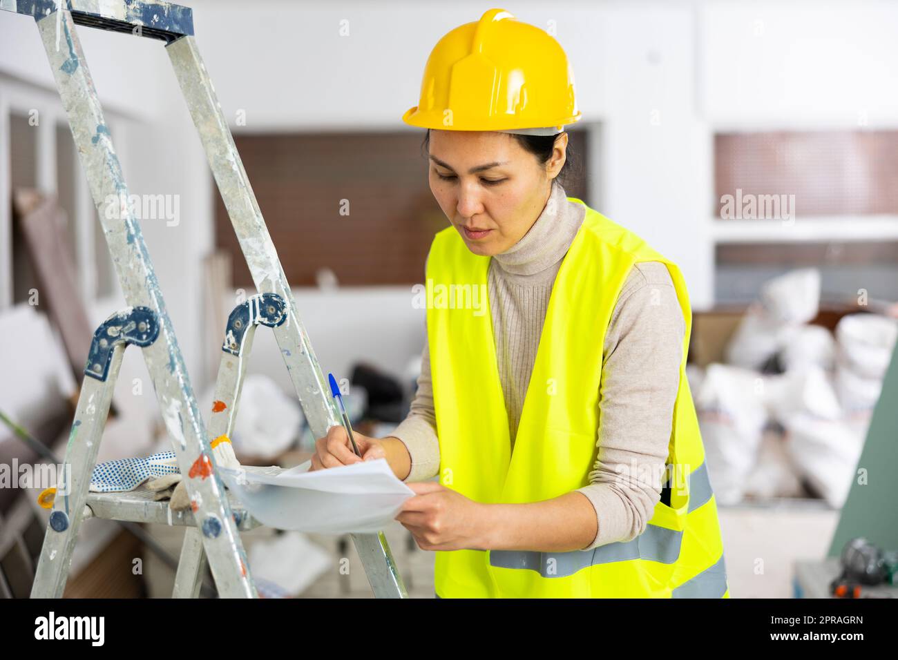 Woman in overalls signs an act of acceptance of completed work Stock ...