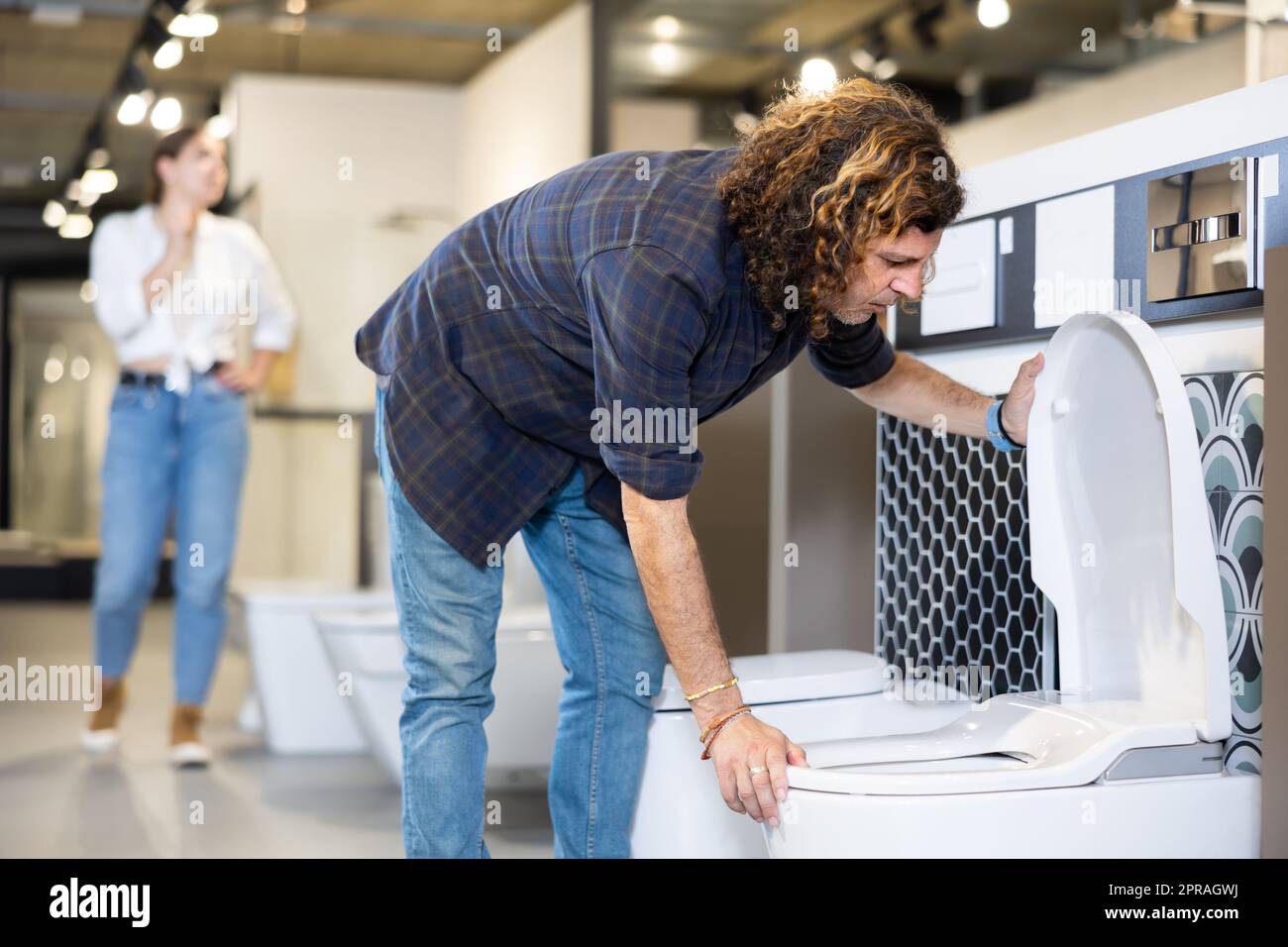 in plumbing department, male buyer checks for defects of toilet before ...
