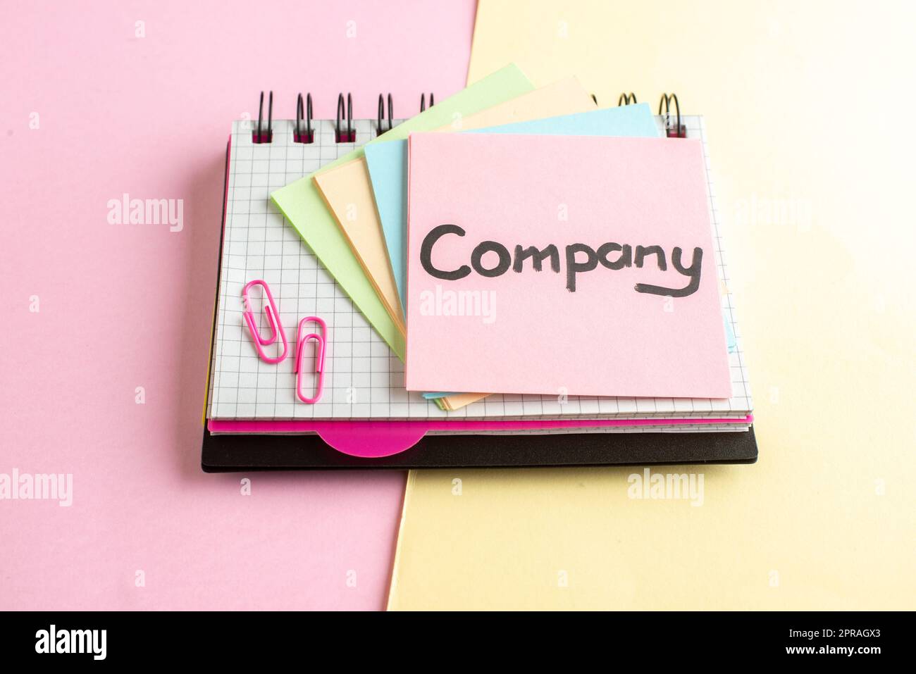 front view company written note with stickers on yellow-pink background ...