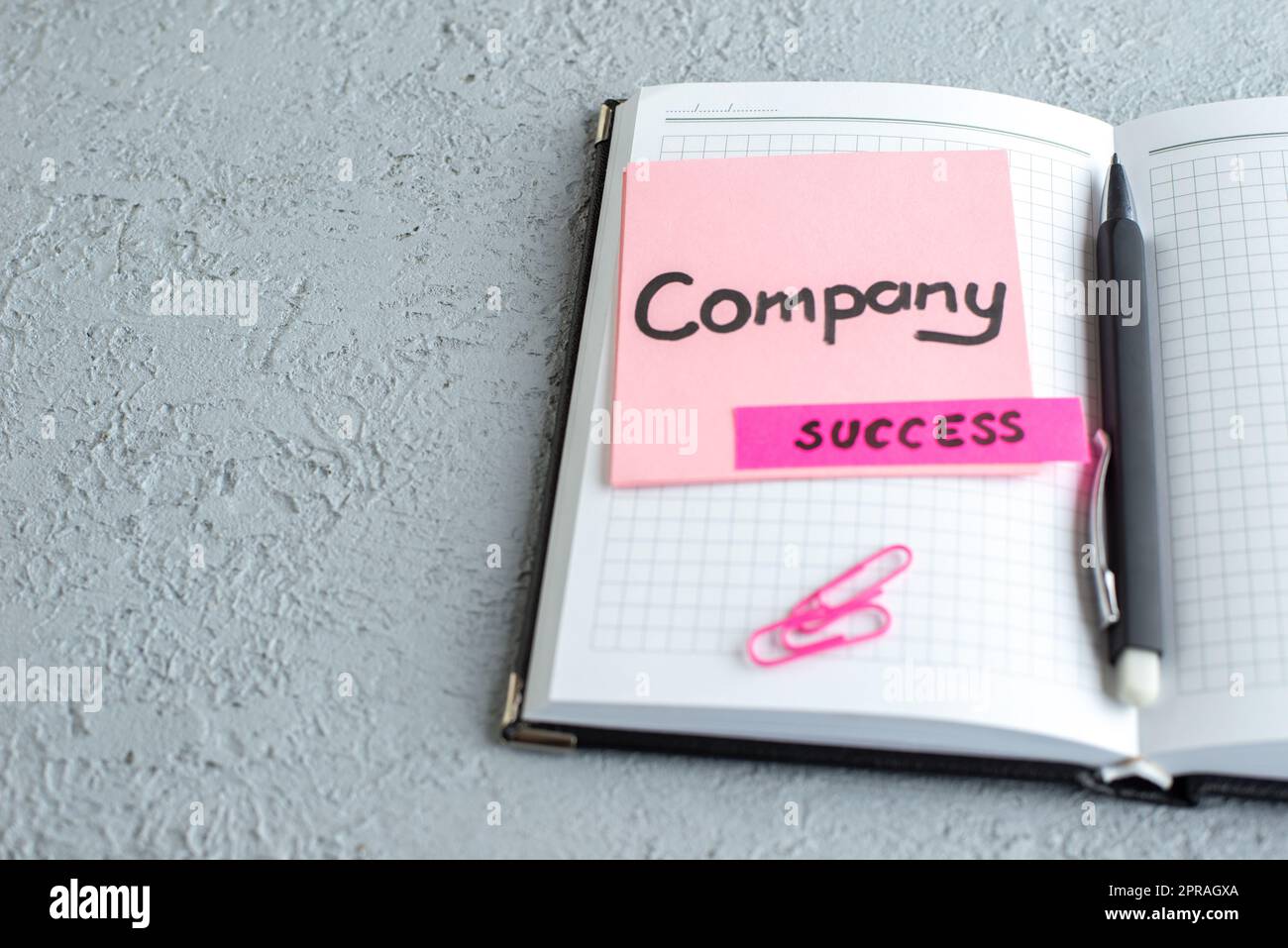 front view company written note with notepad and pen on white ...