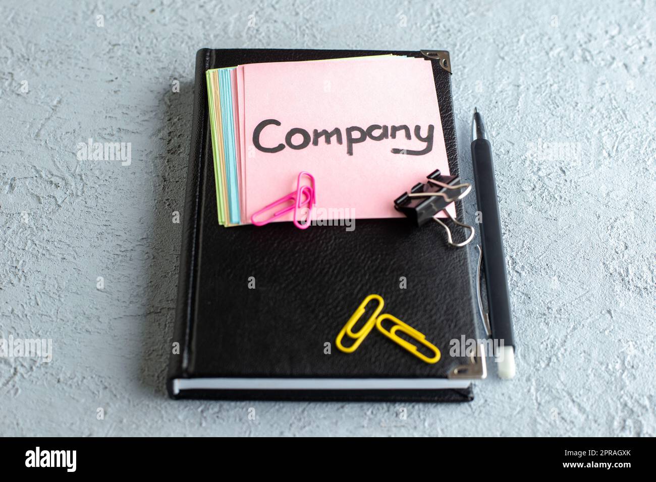 front view company written note with stickers notepad and pen on white ...