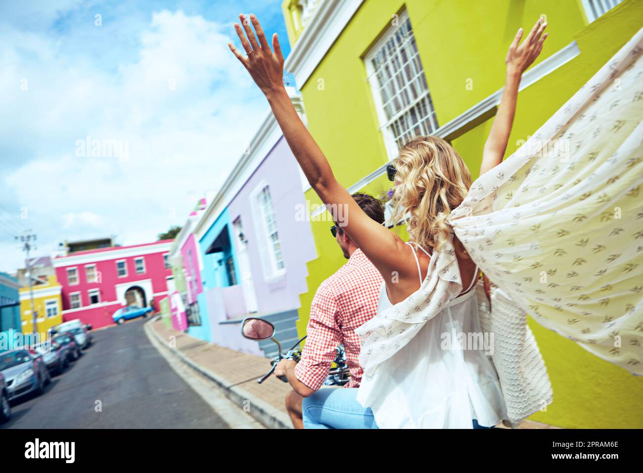 Riding around town. a young couple riding a scooter through colorful ...