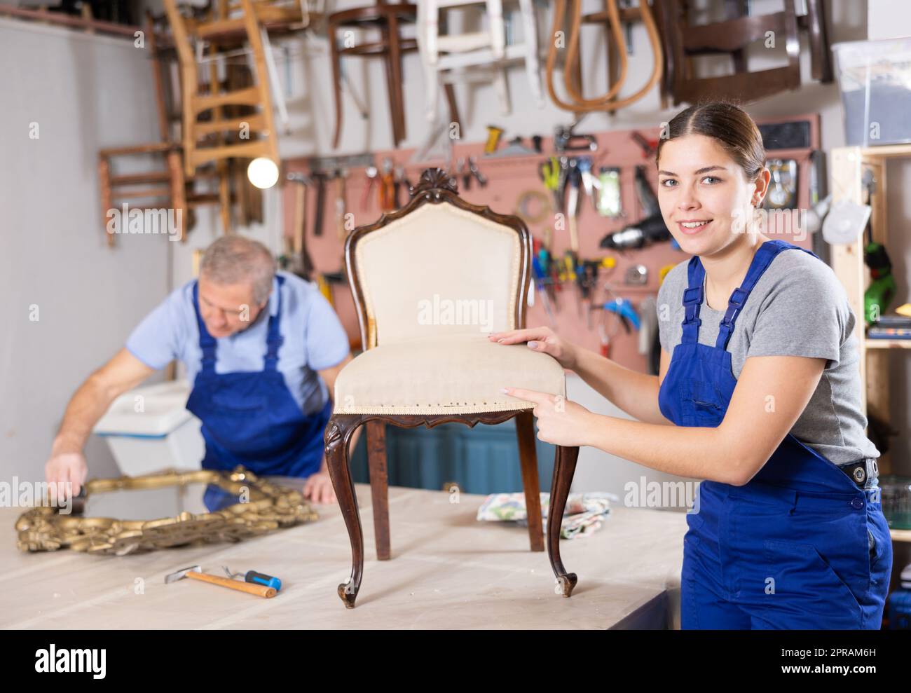 Girl restoration worker dressed in overalls poses in working atmosphere ...