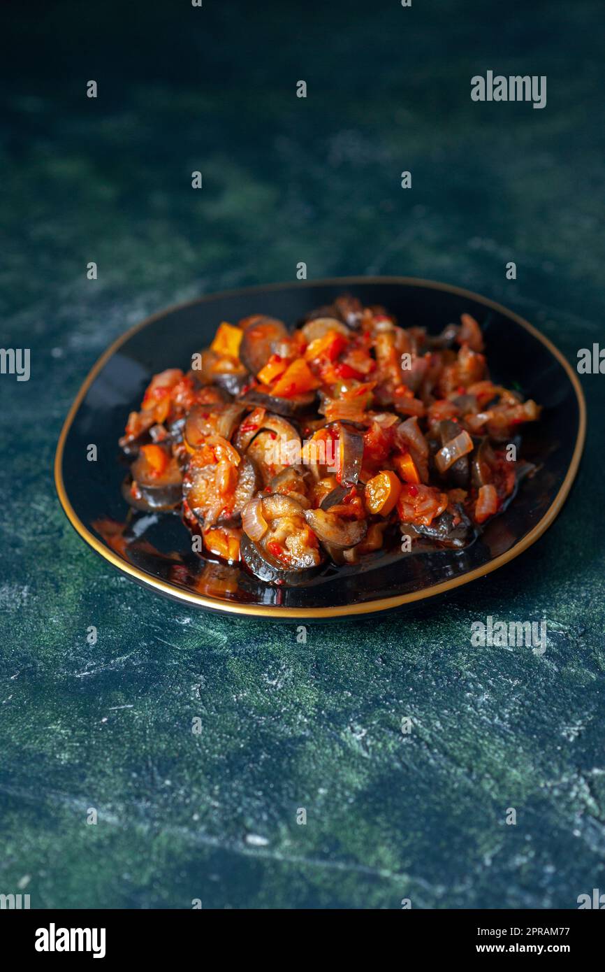 front view sliced cooked eggplants with extra dip inside plate on dark ...