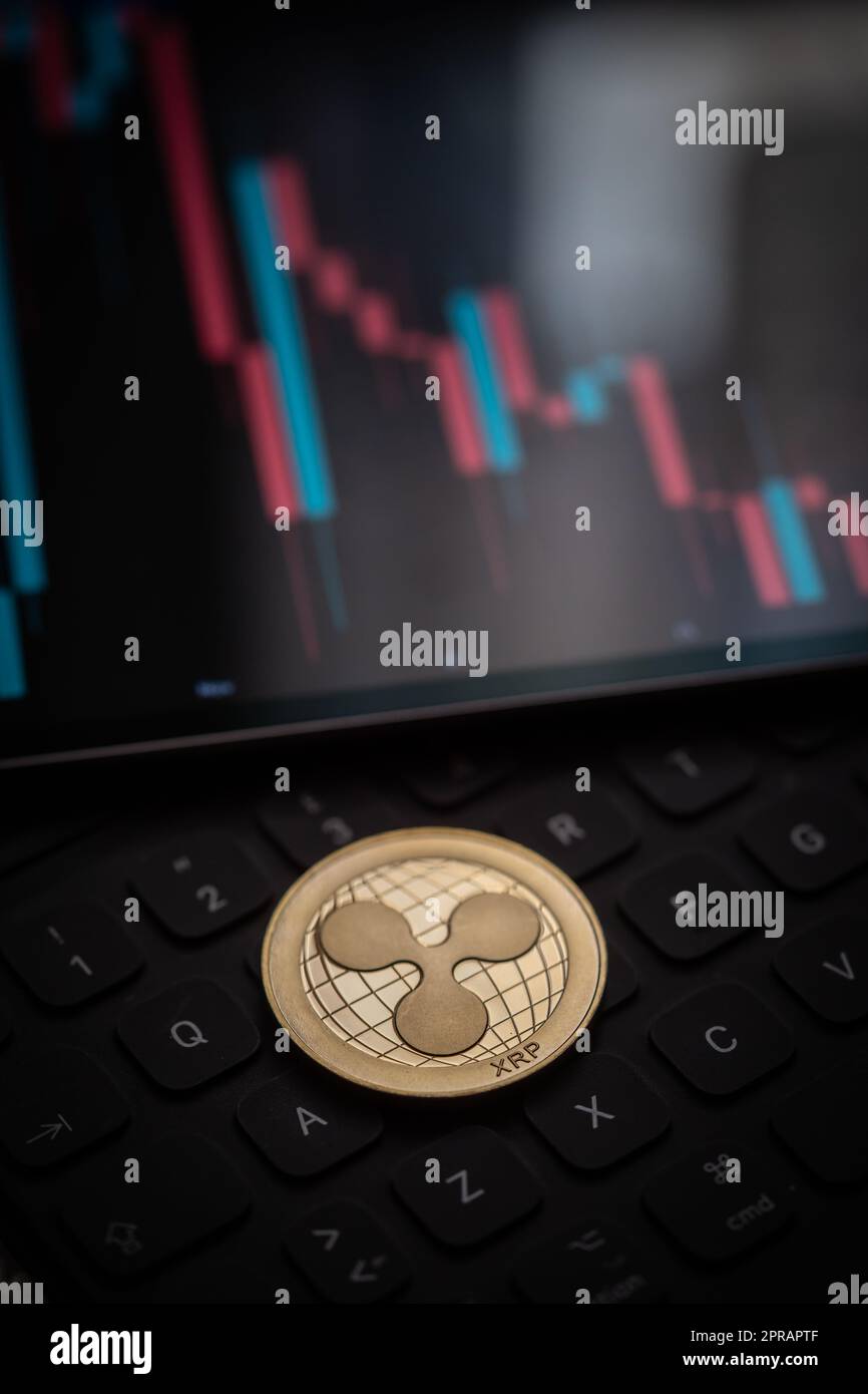 Ripple cryptocurrency coin with candle stick graph chart, laptop ...