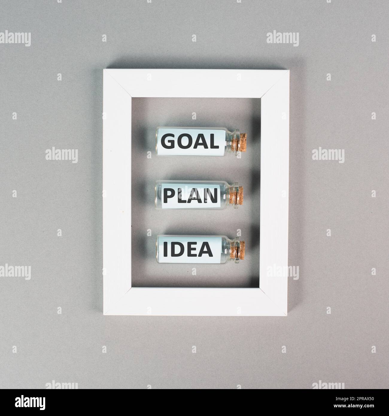 Three glass bottles with the words idea, plan and goal in a frame ...