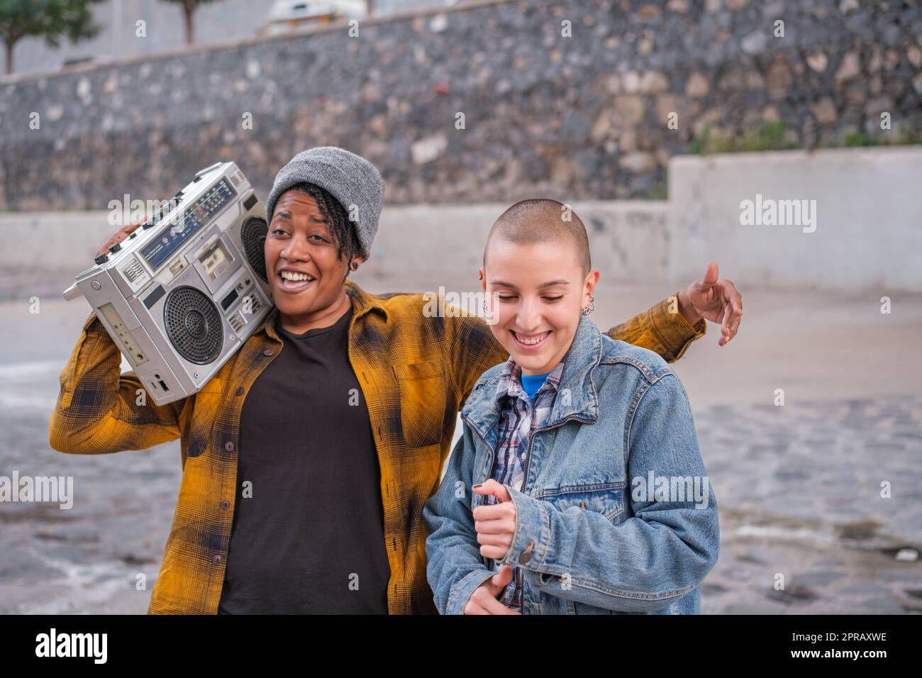 Two women with urban style dancing and singing with a boom box. Concept ...